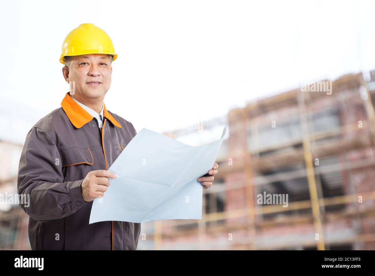 old asian man engineer with blueprint and new construction site Stock ...