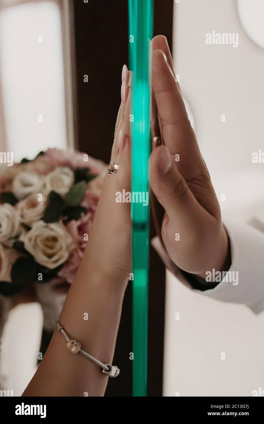 Touching hands of isolated from each other people through the glass ...