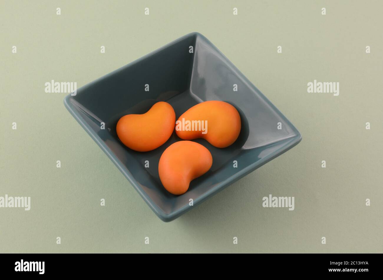 Spicy mango gummy candy pieces sin blue candy dish on green background ...