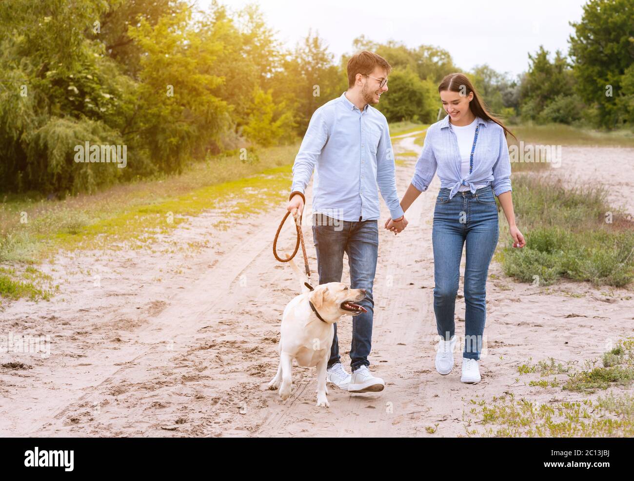 Cute couple and labrador walking together in countryside Stock Photo ...