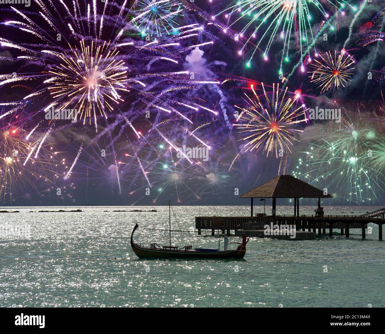 Festive fireworks over the sea and a boat silhouette on water. Maldives ...