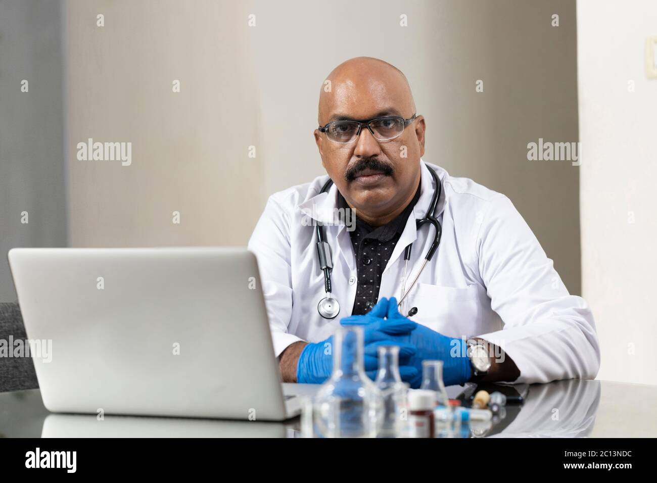 Indian male doctor supporting patients online using phone and computer ...