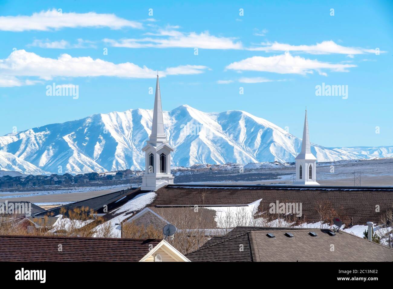Modern spires of church with steep snowy mountain and sunny blue sky ...