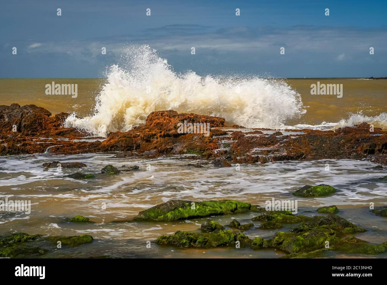 Strong wave hitting rocks on the beach Stock Photo - Alamy