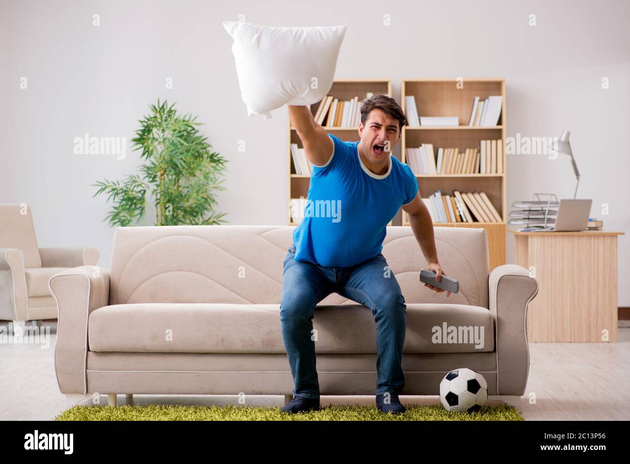 Man watching football at home sitting in couch Stock Photo - Alamy