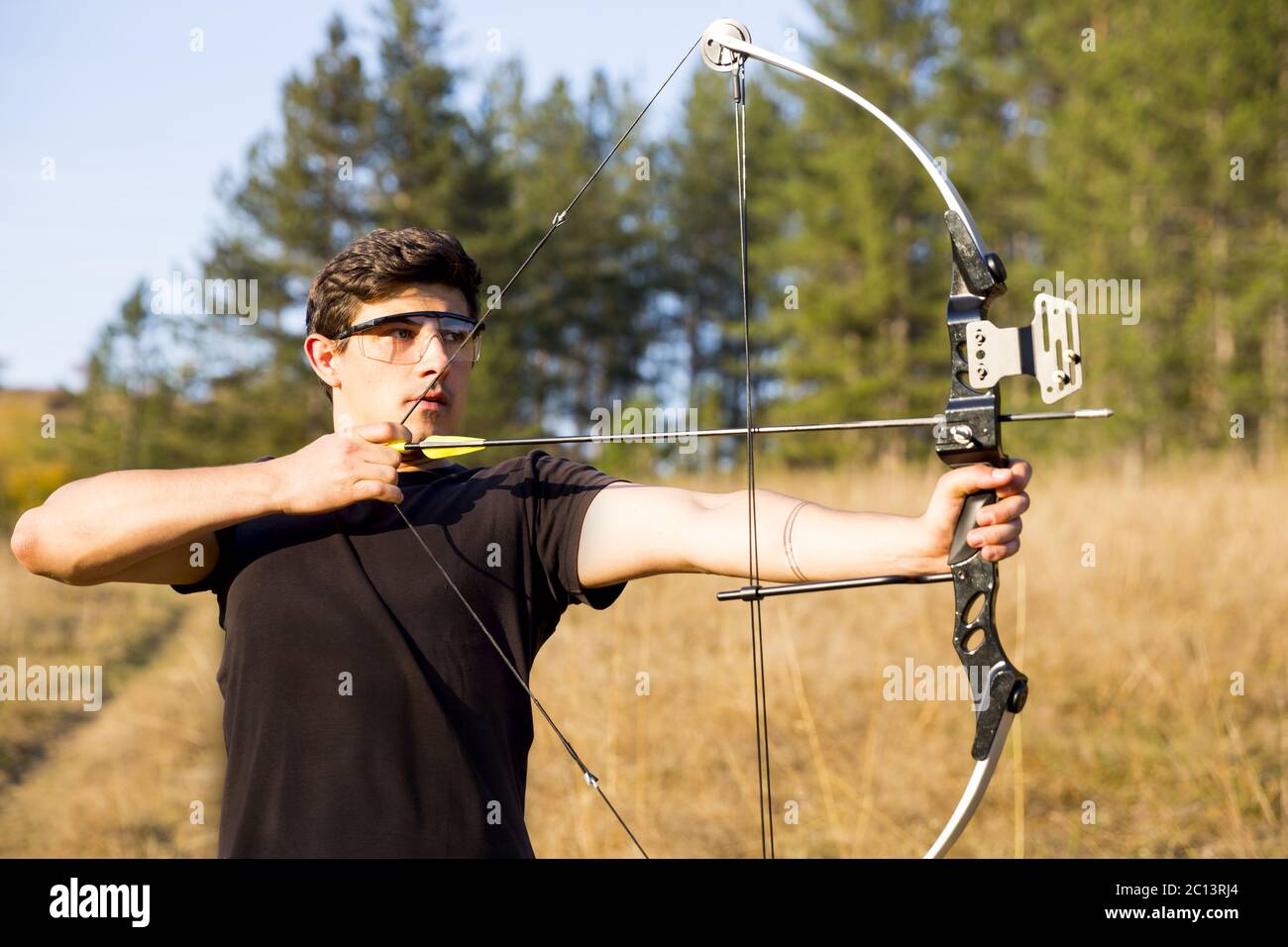 Archer drawing his compound bow trees Stock Photo - Alamy