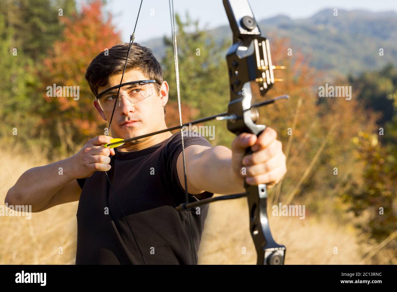 Archer drawing his compound bow trees Stock Photo - Alamy