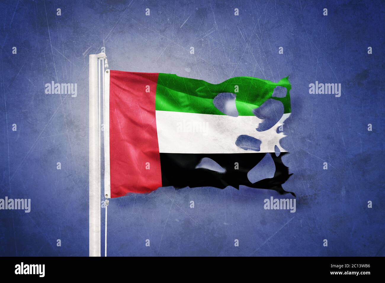 Torn flag of United Arab Emirates flying against grunge background ...