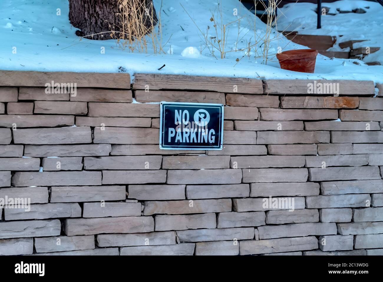 No Parking sign on a stone brick retaining wall topped with snow in ...