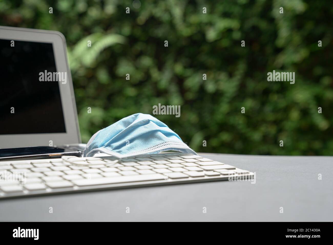Medical face mask on top of computer laptop and keyboard. Work at home ...