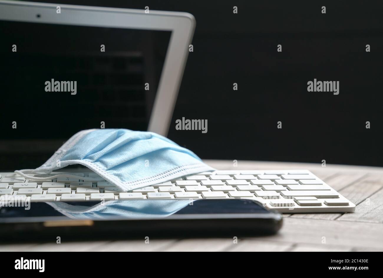 Medical face mask on top of computer laptop keyboard and cellphone ...