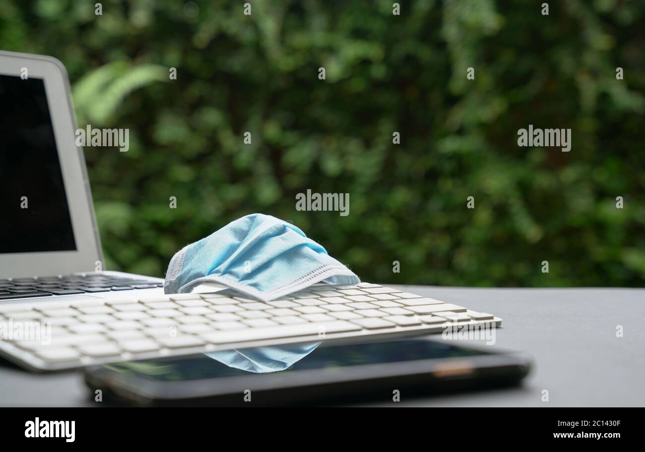 Medical face mask on top of computer laptop keyboard and cellphone ...