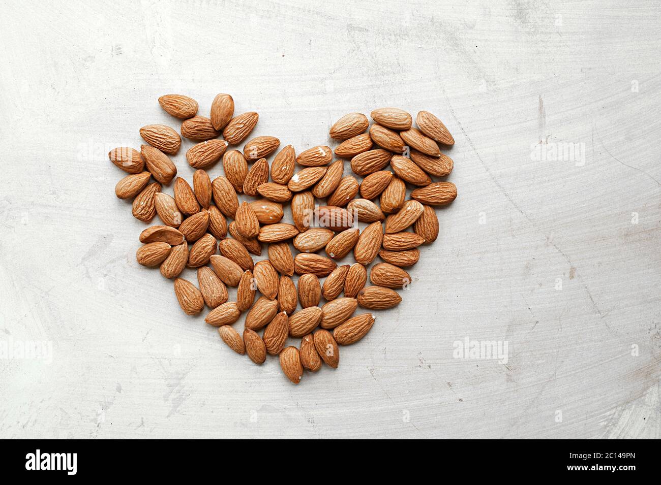 almonds nut laid out in the shape of a heart on a light concrete ...