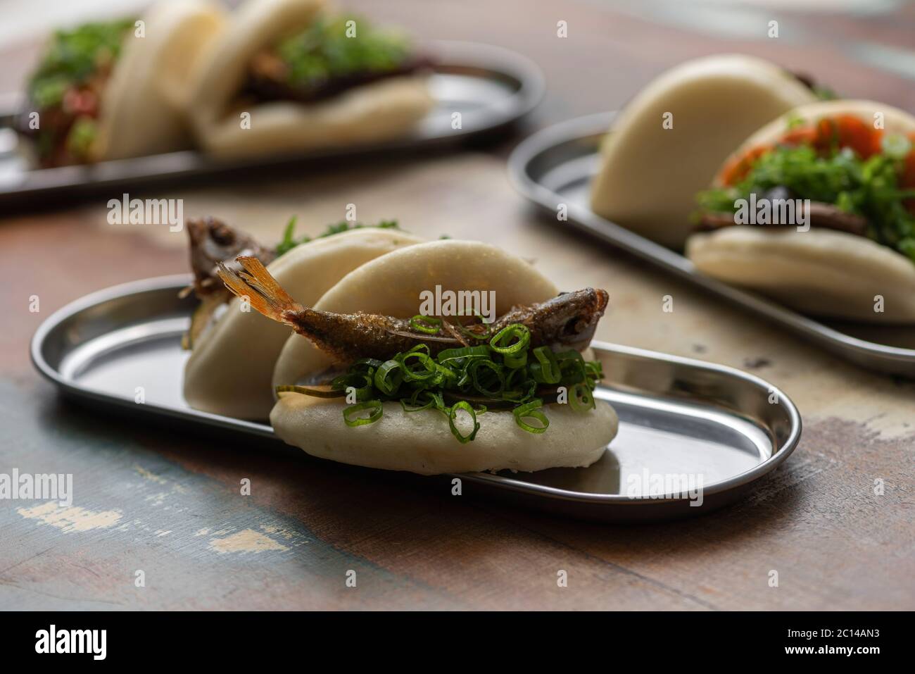 two asian bao stuffed with fried entire fish and fermented kimchi ...