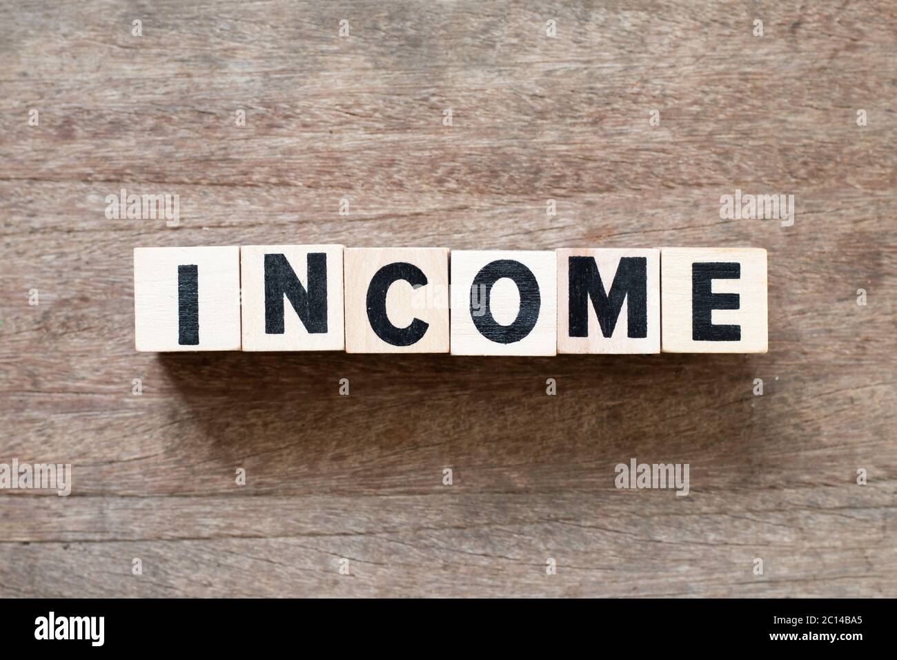 Letter block in word income on wood background Stock Photo - Alamy