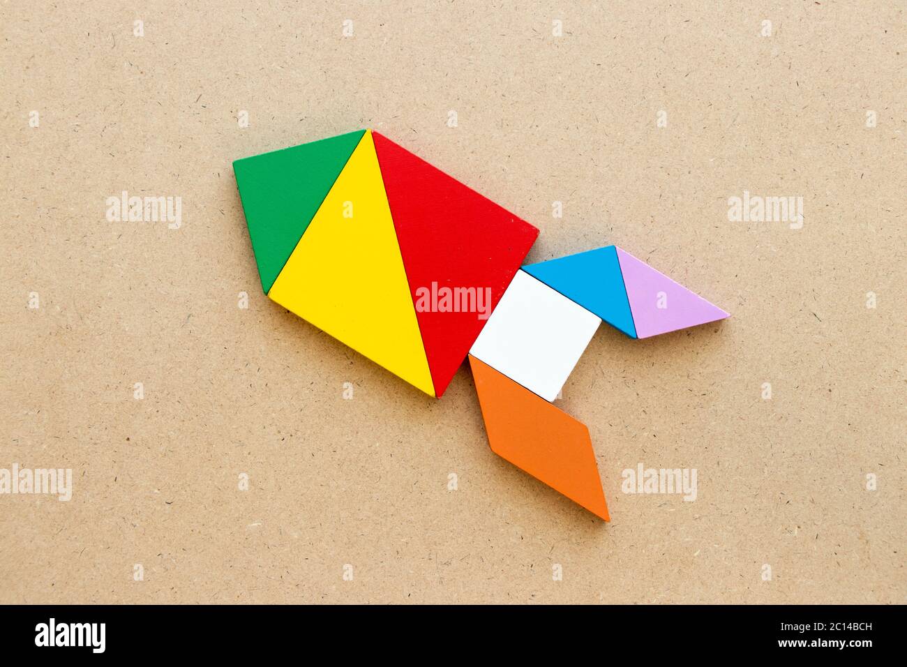 Color tangram puzzle in rocket or missile shape on wood background ...