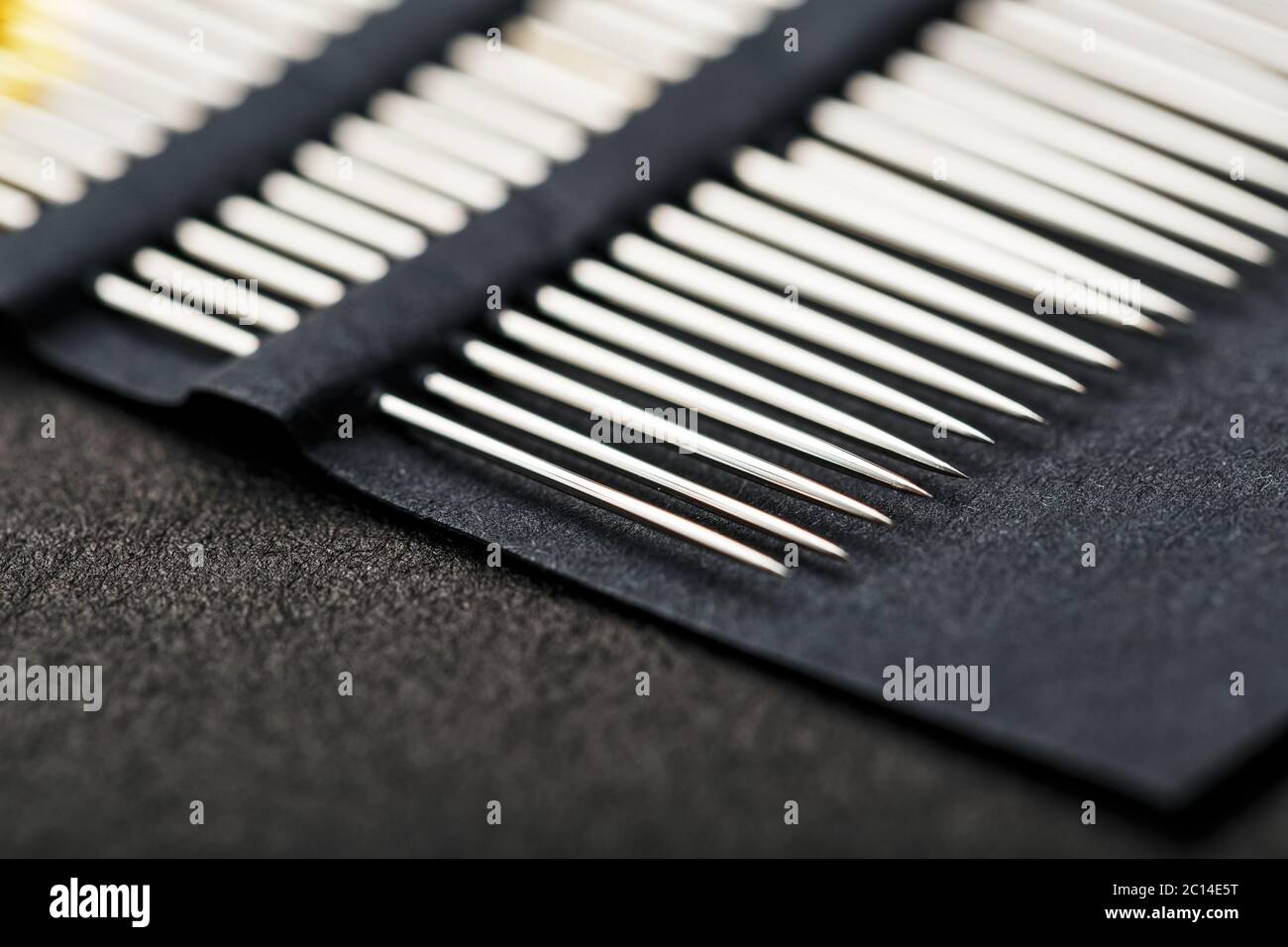Sewing needles on a black background in a row Stock Photo - Alamy