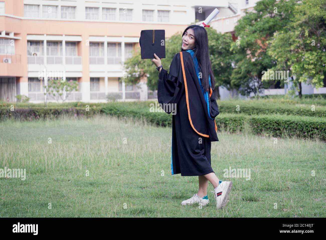 Portrait of happy and excited of young Asian female university graduate ...