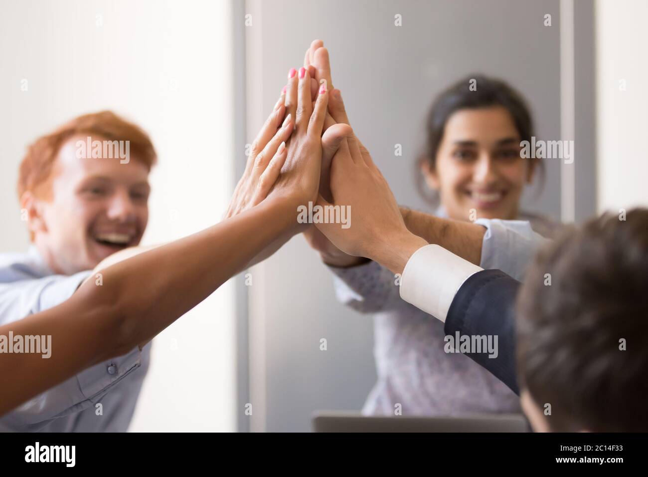 Happy diverse employees giving high five, celebrating success Stock ...