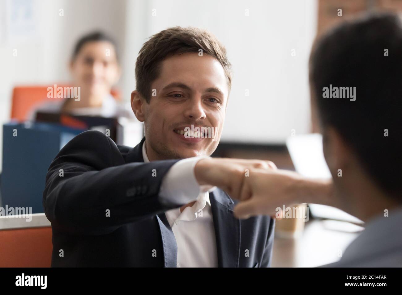 Smiling businessman employee fists bumping with colleague close up ...