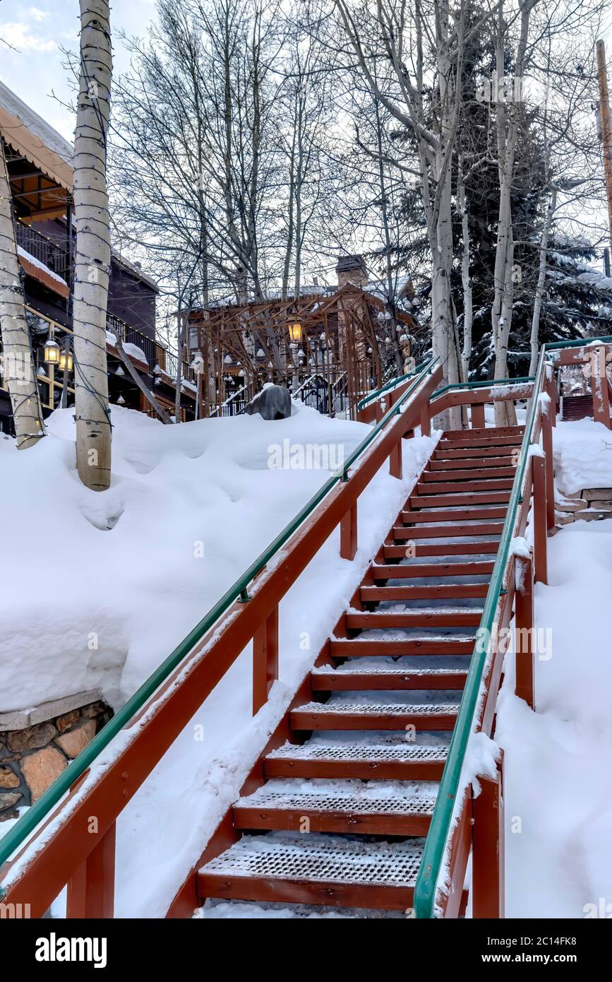 Outdoor stairs on snowy slope against buildings and trees on cloudy ...