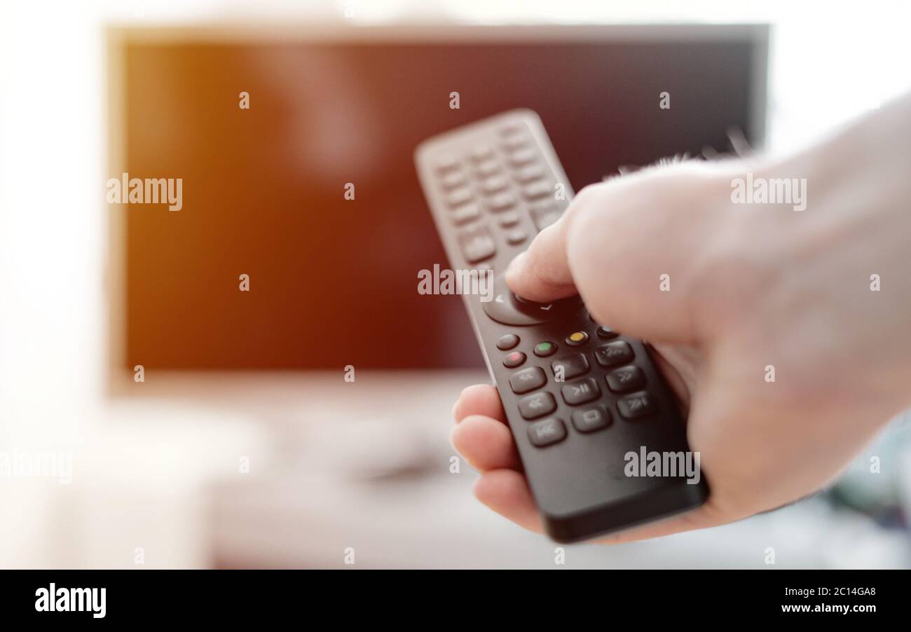 Hand holding use remote control and watching TV in house with warm and ...