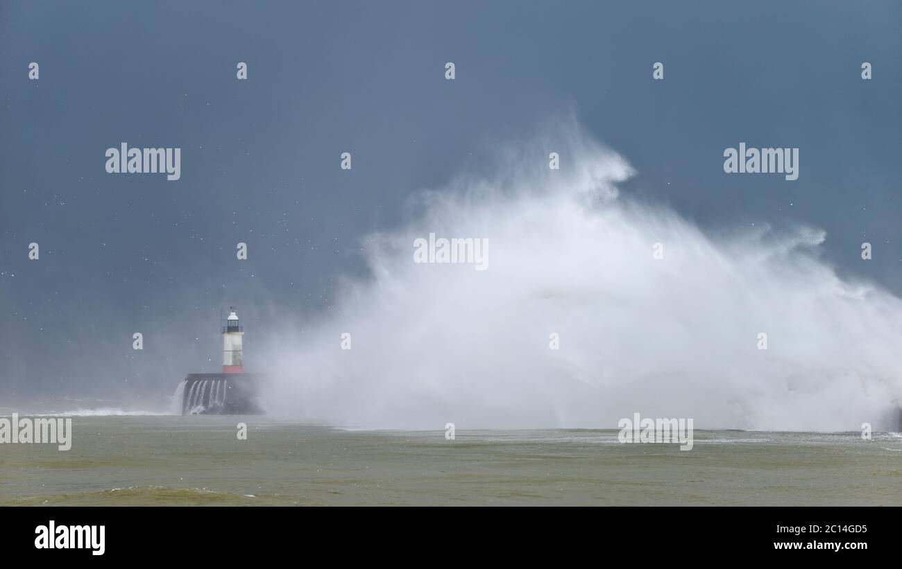 Huge waves crash over harbour wall onto lighthouse during huge storm on ...