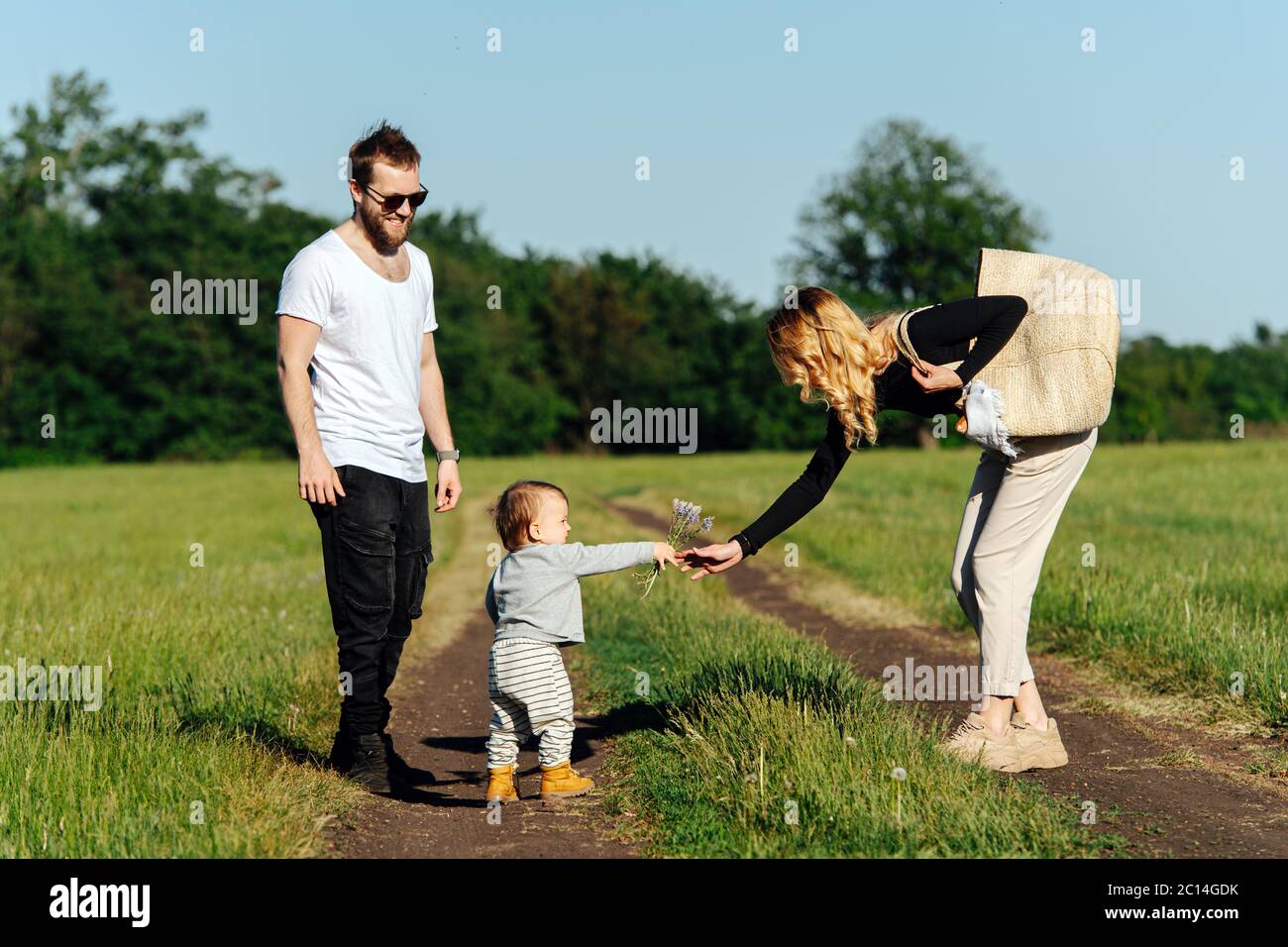 Little baby boy giving her mother wild flowers. On a sunny summer day ...