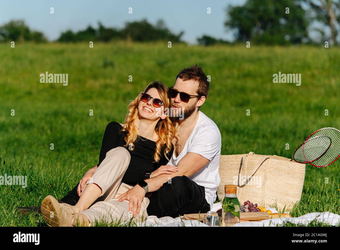 Cute couple sitting on a blanket on a grass field, enjoying views Stock ...