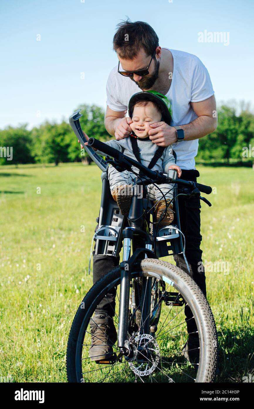 Father playing with his grumpy kid, pinching and lifting his cheeks in ...