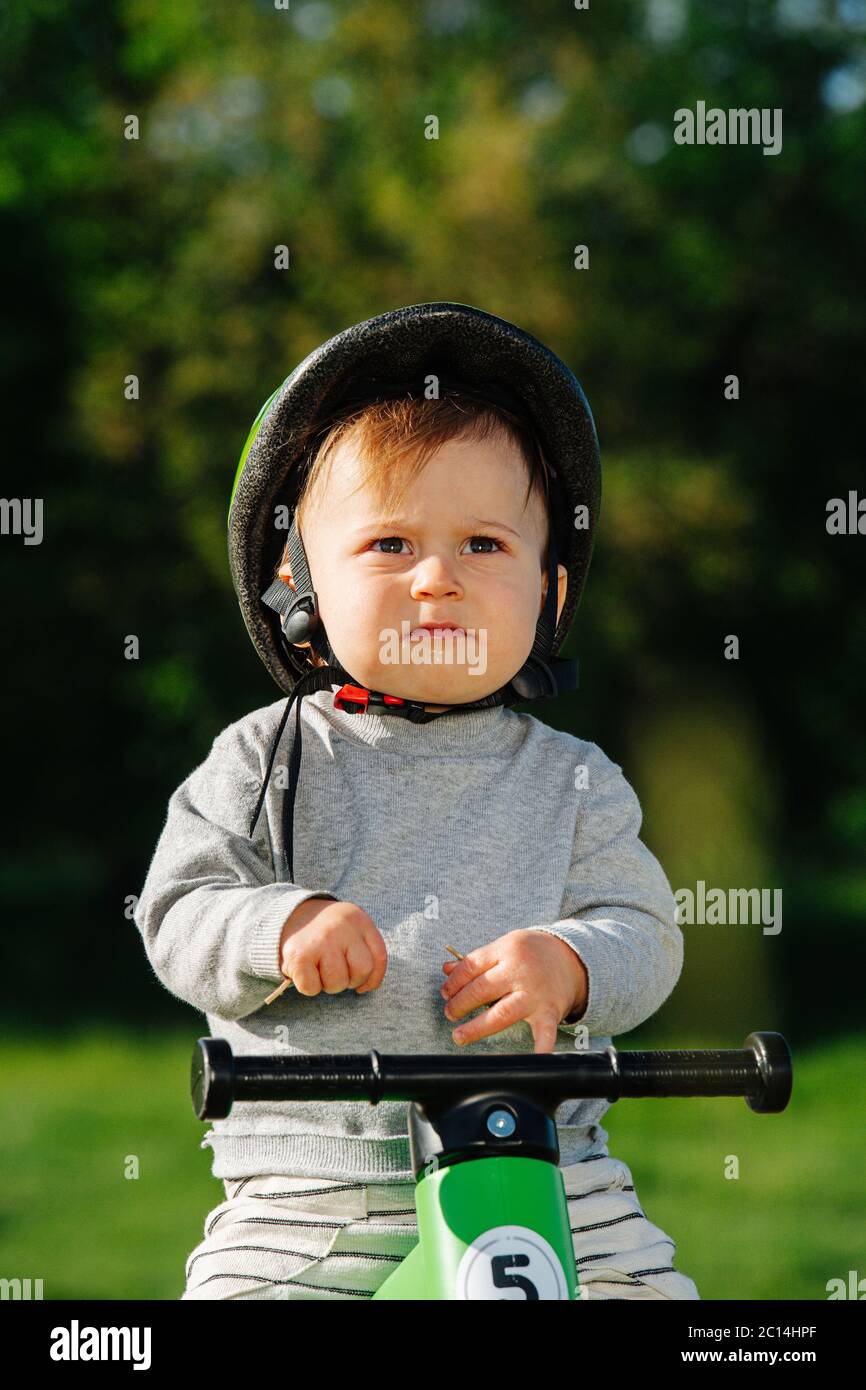 Grumpy little kid sitting on a three-wheel foot bike Stock Photo - Alamy