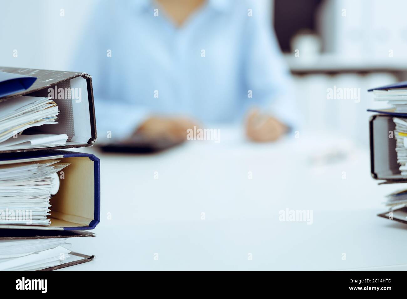 Binders with papers are waiting to be processed by business woman or ...