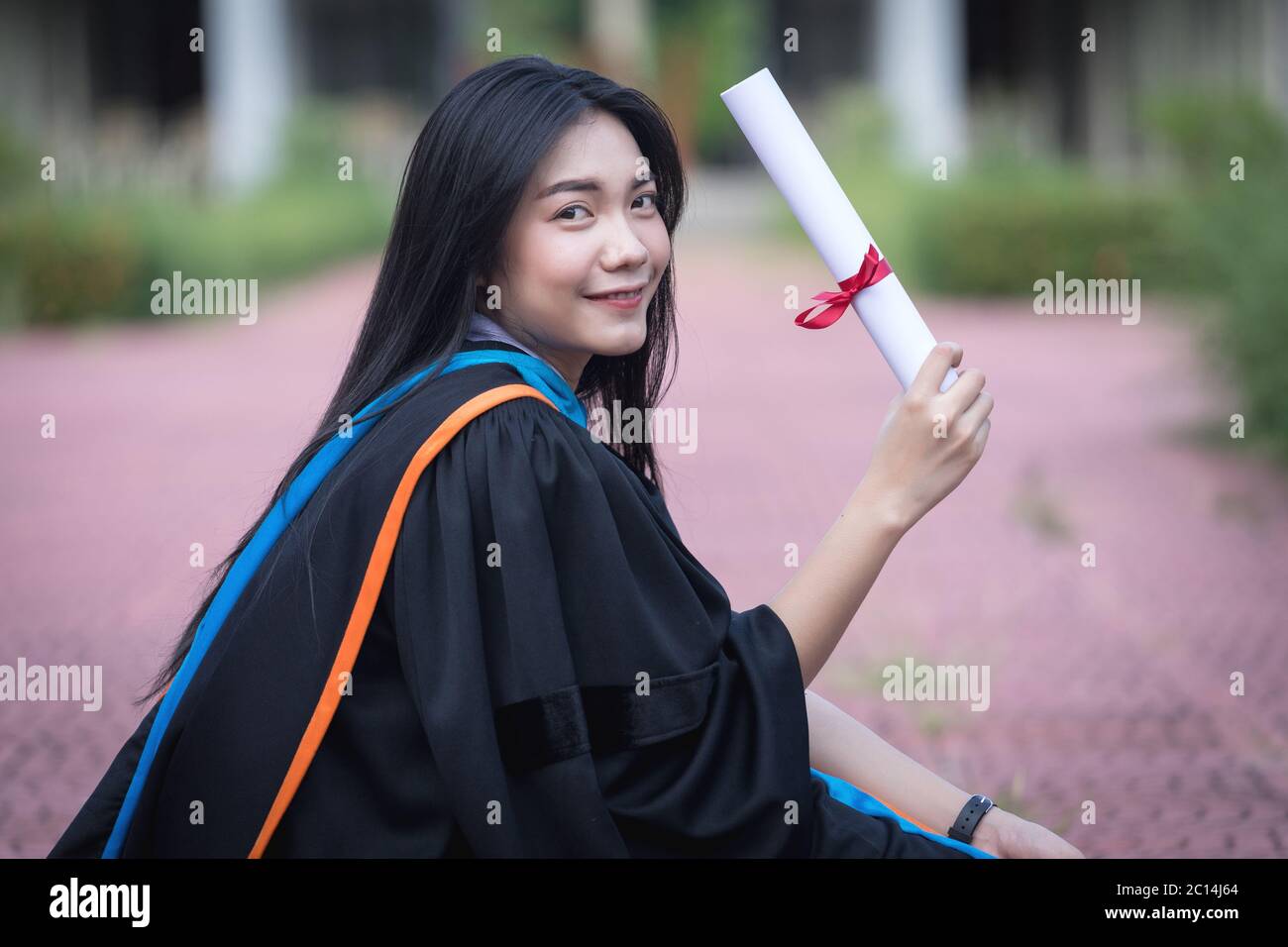 Portrait of happy and excited of young Asian female university graduate wears graduation gown ...