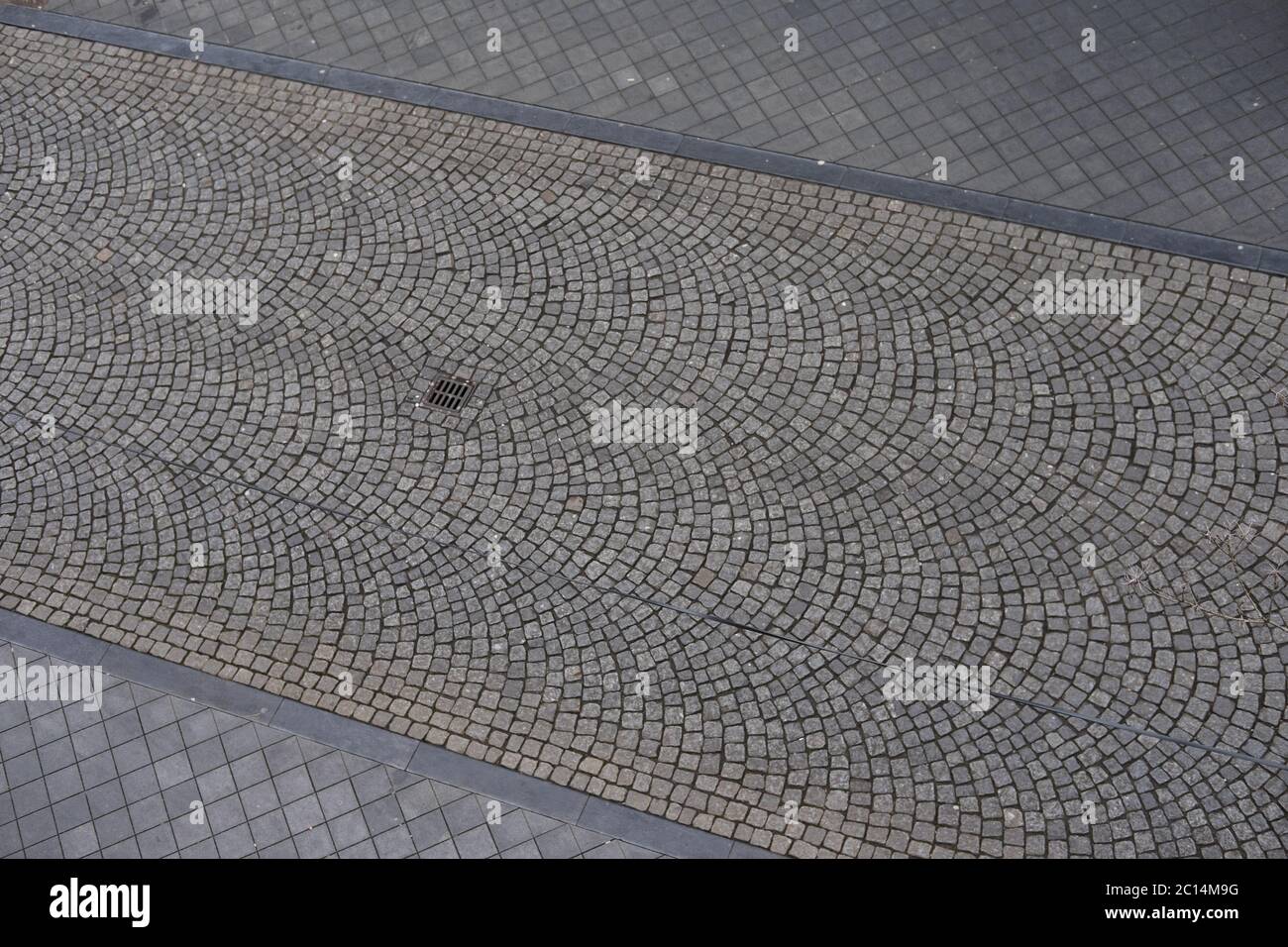 Street with old paving stones and cast iron lid of water drain seen ...