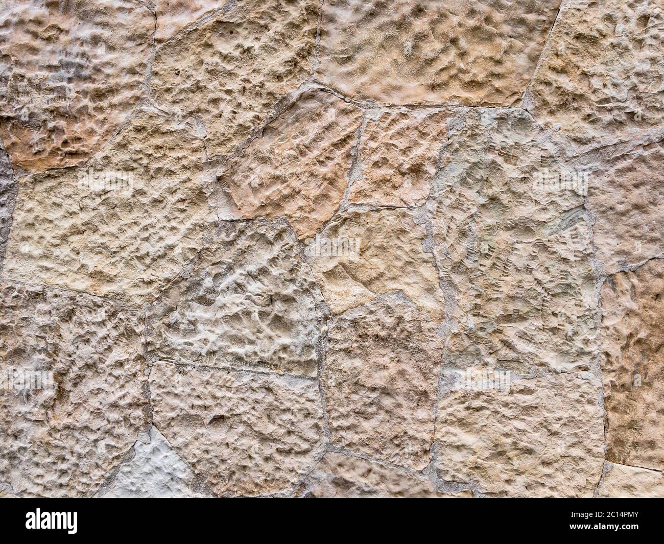 Brown wall of stone blocks of irregular shape and uneven surface for ...