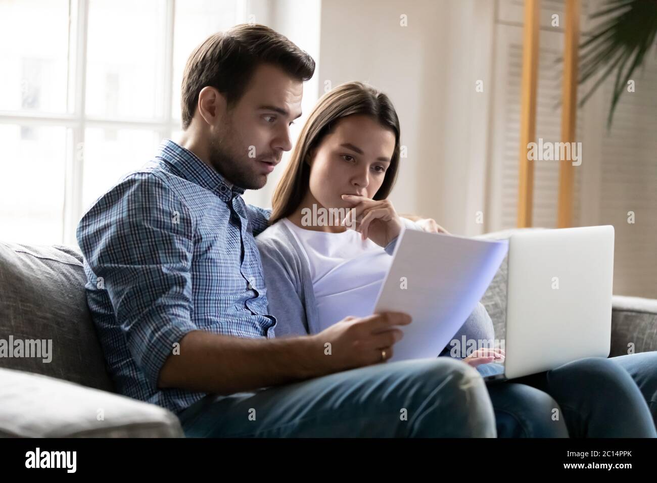 Shocked worried young couple reading documents, financial problems ...