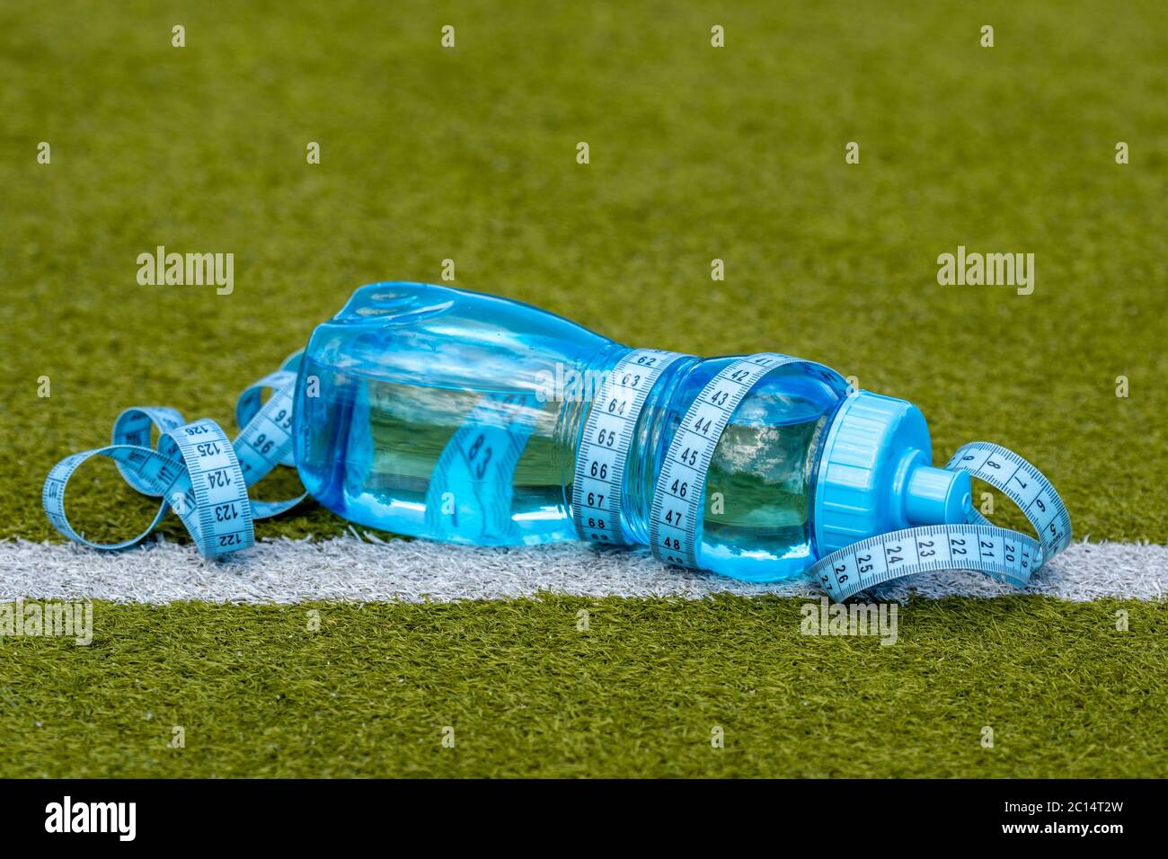 Plastic bottle of water with measure tape on green artificial grass at ...