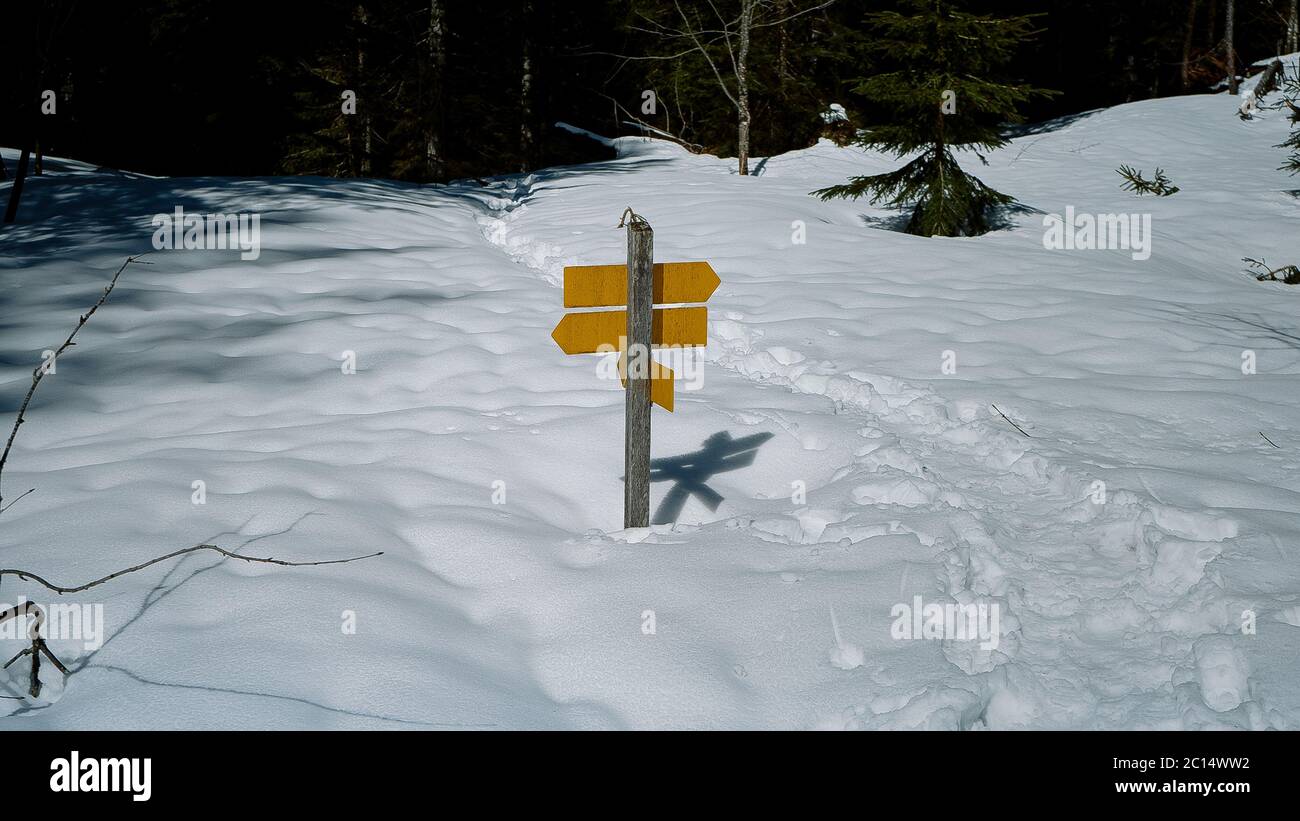 Yellow mountain guidepost along the alpine pathway over snowy landscape ...
