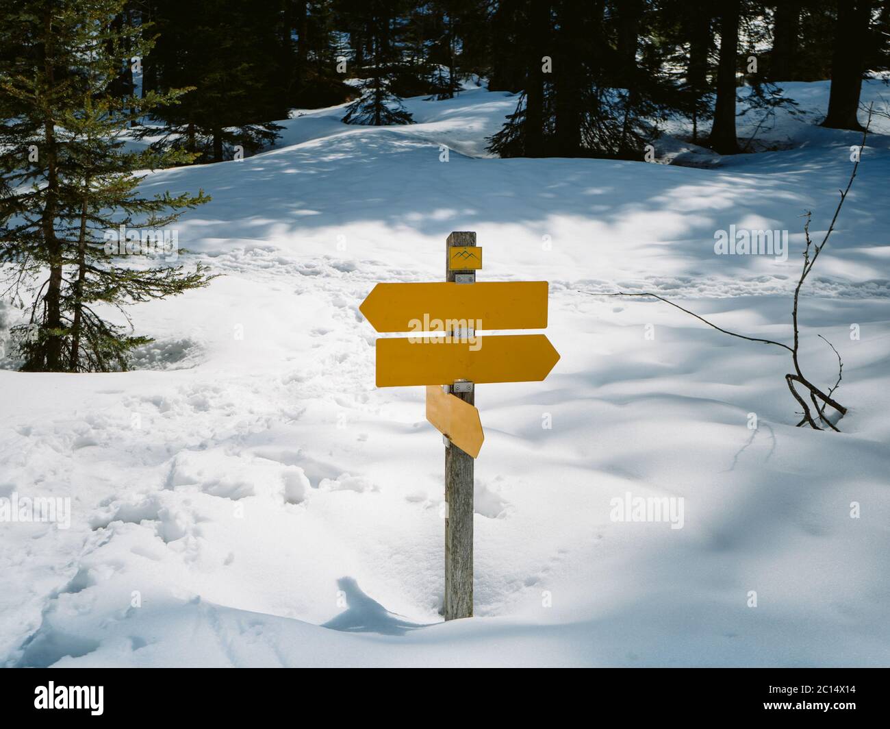 Yellow mountain guidepost along the alpine pathway over snowy landscape ...