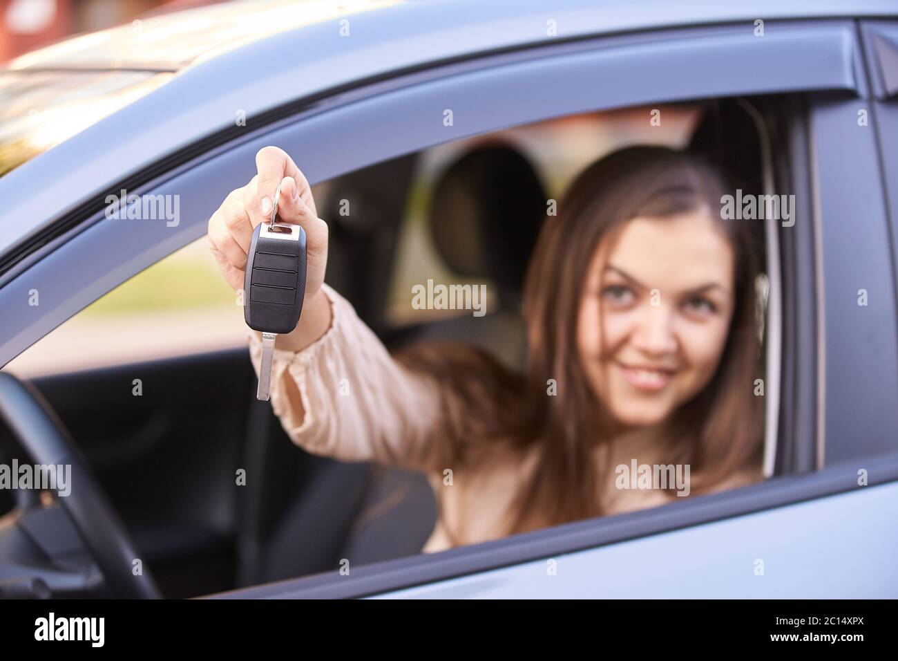 Young woman in car. Ride instruction. Automobile loan. Hand with key ...