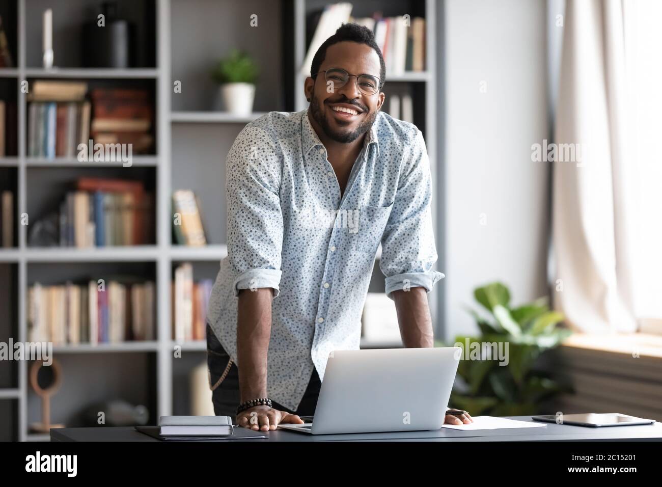African man standing leaned over laptop smiling looking at camera Stock ...