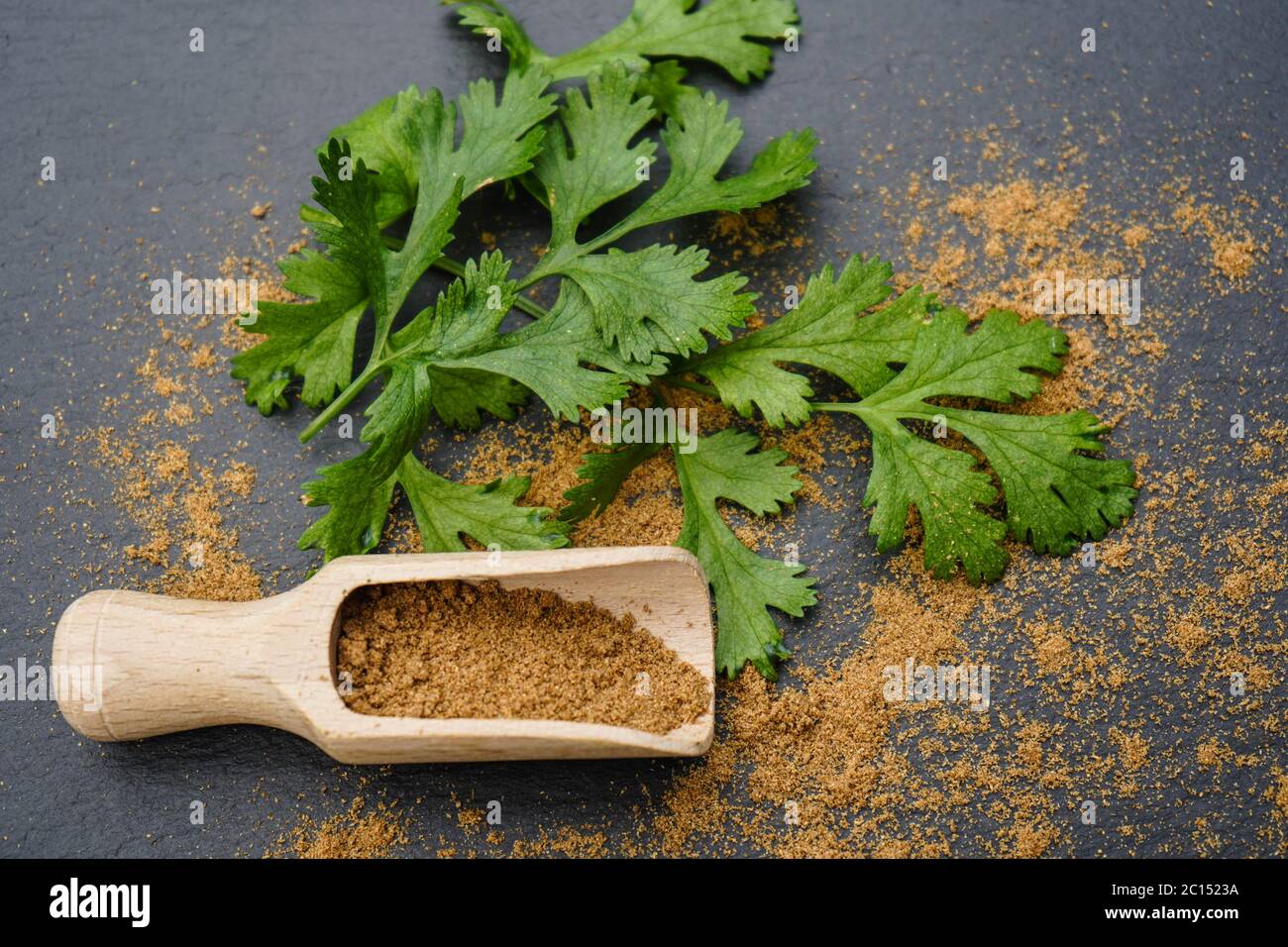 Brown coriander powder and wooden spoon Stock Photo - Alamy