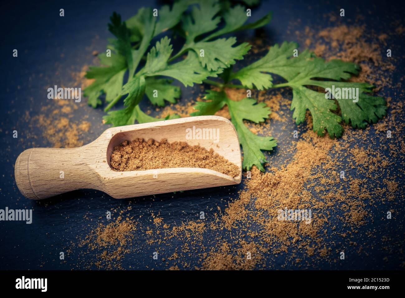 Brown coriander powder and wooden spoon Stock Photo - Alamy