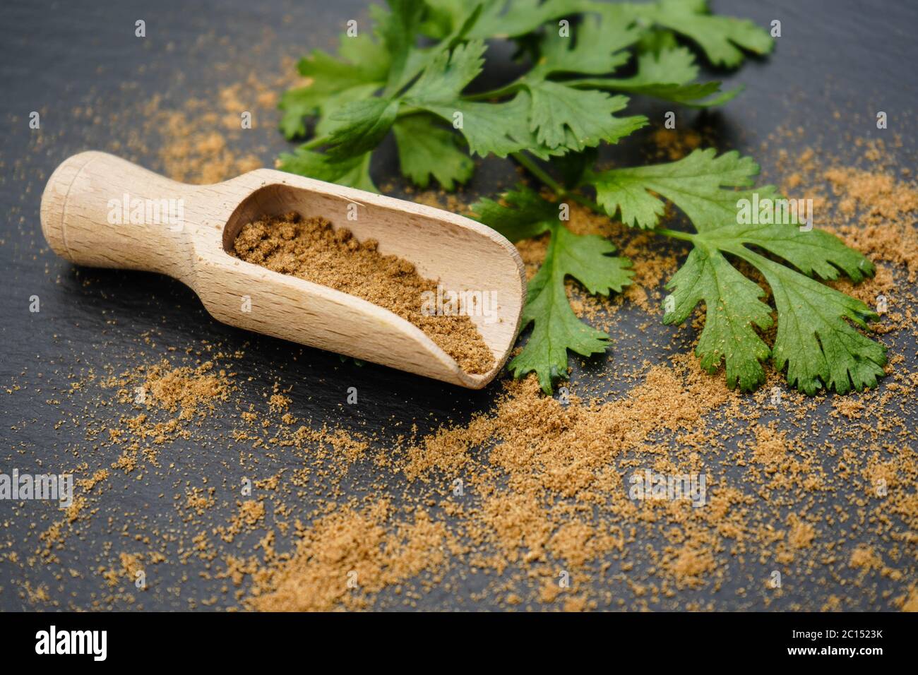 Brown coriander powder and wooden spoon Stock Photo - Alamy