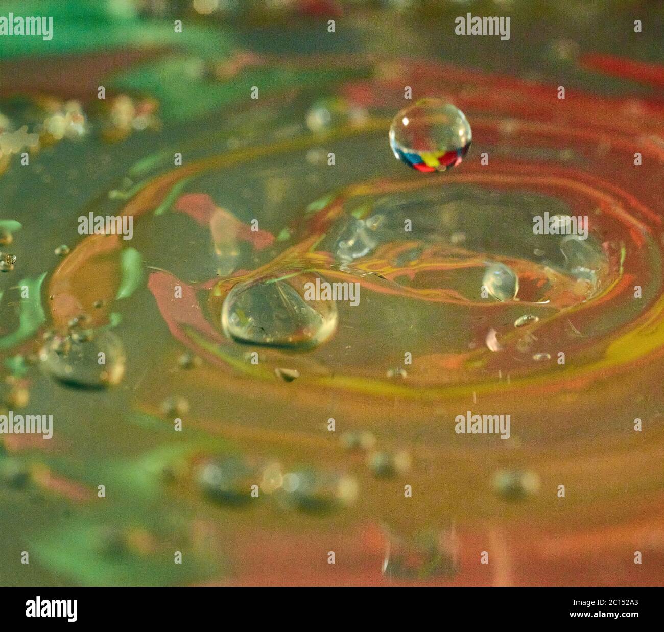 Water droplets falling on and bouncing off a pool of water, leaving ...