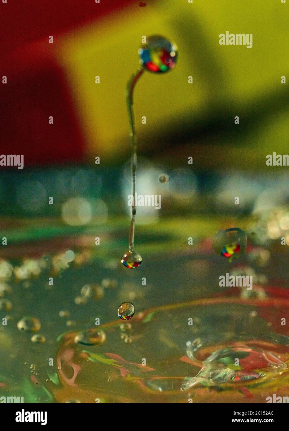 Water droplets falling on and bouncing off a pool of water, leaving ...