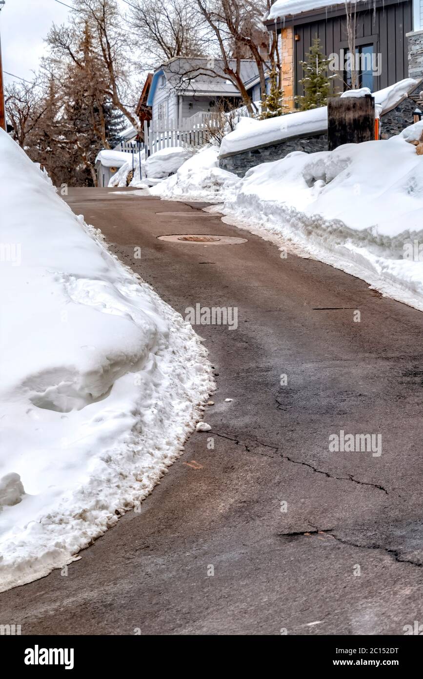 Residential landscape with paved road along mounds of snow and houses ...