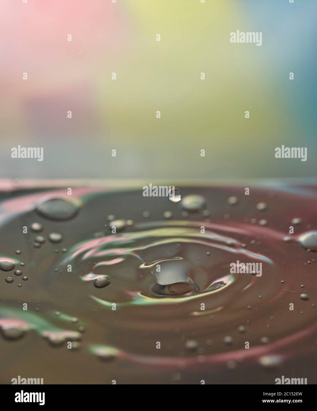 Water droplets falling on and bouncing off a pool of water, leaving ...