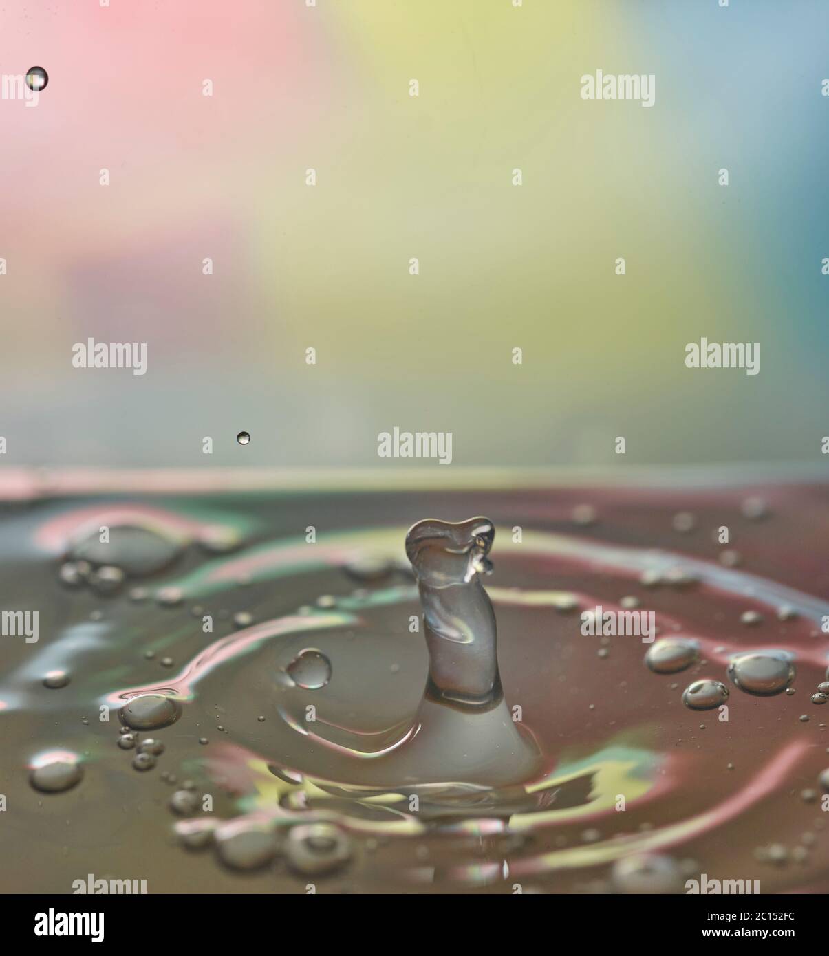 Water droplets falling on and bouncing off a pool of water, leaving ...