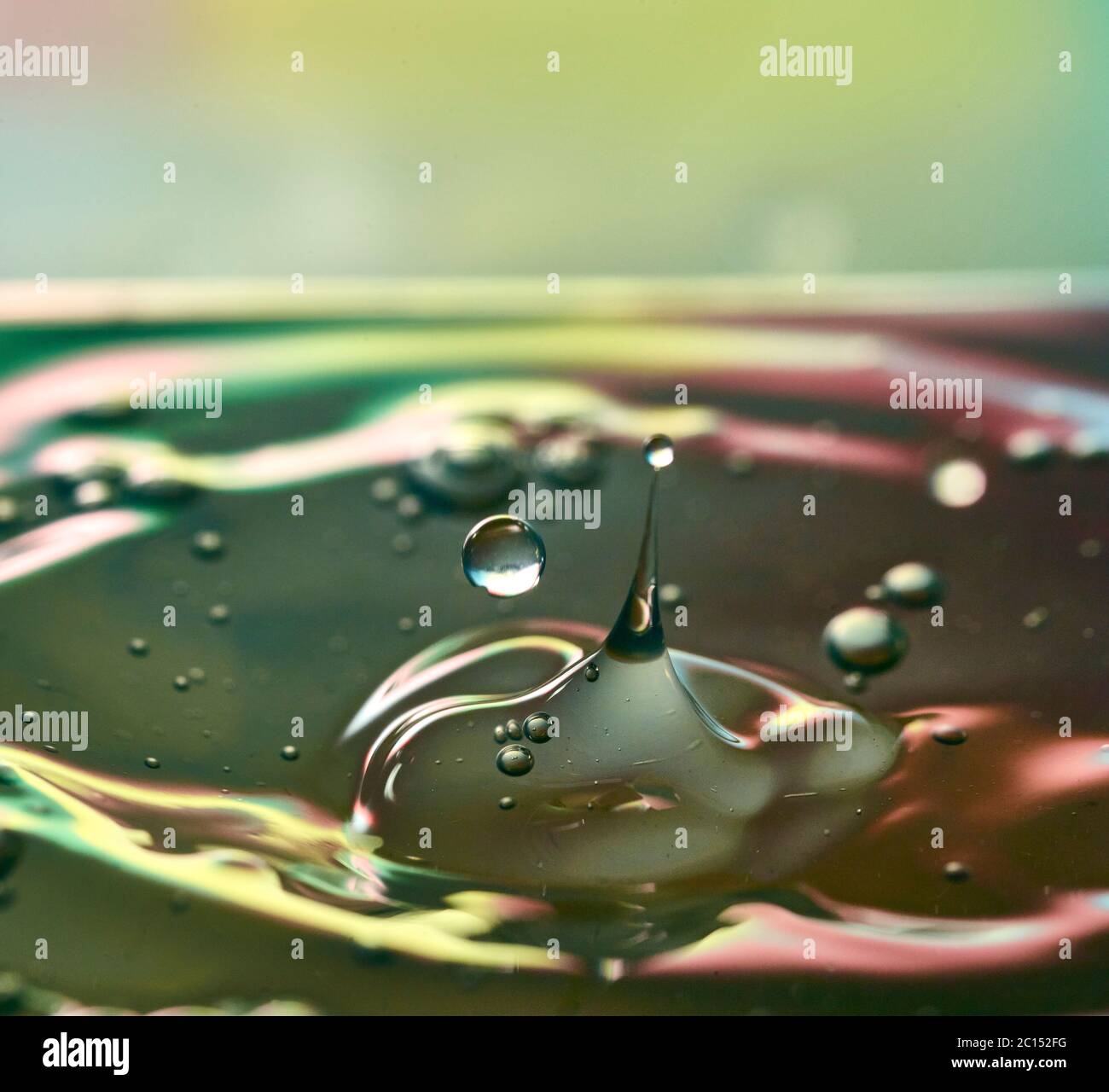Water droplets falling on and bouncing off a pool of water, leaving ...